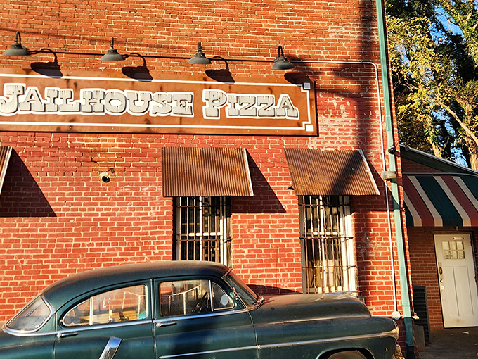 The iconic brick facade of Jailhouse Pizza, complete with vintage car, makes you wonder if Al Capone would've approved of their crust technique.