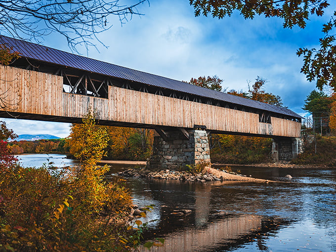 The historic Blair Covered Bridge welcomes travelers with its weathered charm and distinctive architecture, a wooden time portal spanning the Pemigewasset River.