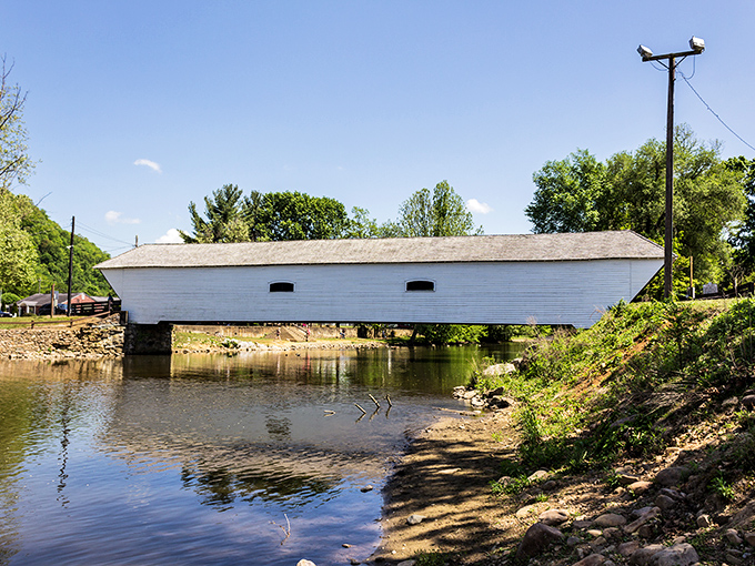 The gleaming white Elizabethton Covered Bridge stretches across the Doe River like a postcard come to life, reflecting perfectly in the calm waters below.