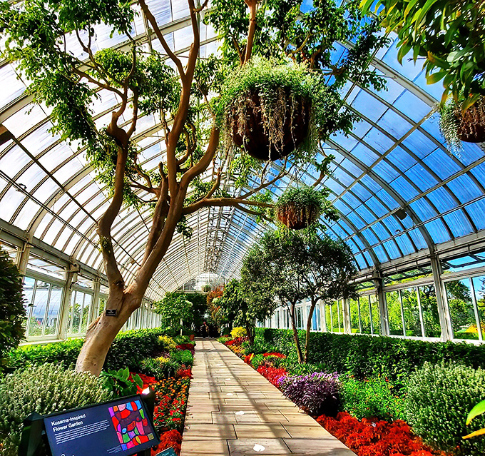 A stone pathway flanked by roses leads to a gazebo that looks like it was designed by someone who read too many Jane Austen novels—in the best possible way.