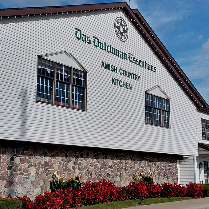 A closer view reveals the stone foundation and vibrant flower beds that welcome hungry travelers to this Amish Country Kitchen landmark.
