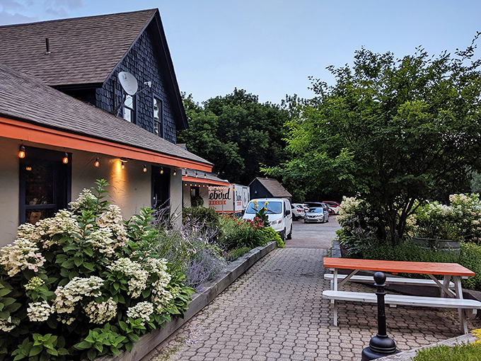 Vermont charm meets barbecue heaven at Bluebird's inviting exterior. Hydrangeas and string lights welcome you to this shingled sanctuary of smoke and flavor.