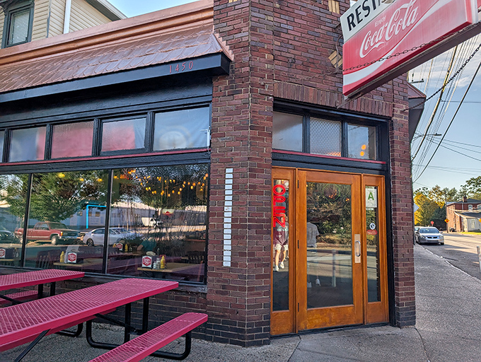 Burger Boy's charming brick exterior features wooden doors and large windows, with red picnic tables offering a casual spot to enjoy Louisville's best burgers.