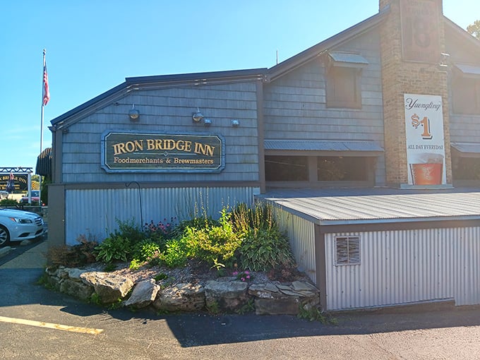 The Iron Bridge Inn stands proudly under Pennsylvania's blue skies, its distinctive black awnings and stone foundation promising culinary adventures within.