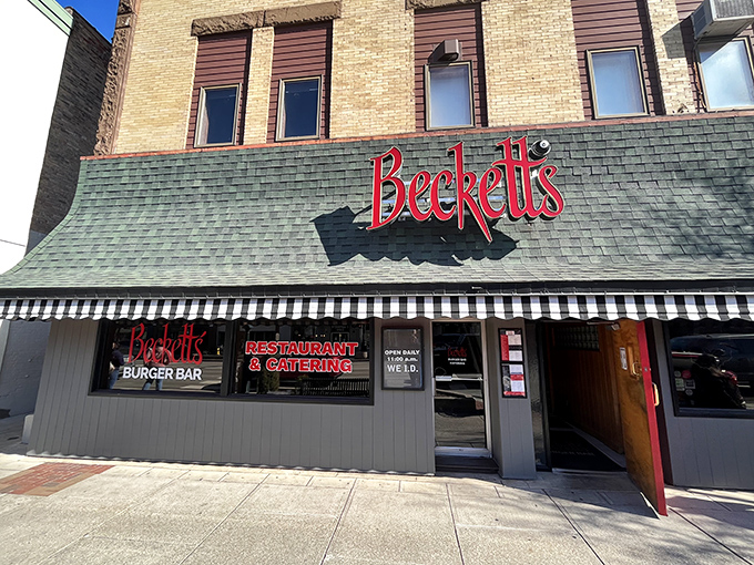 The classic brick façade of Beckett's welcomes hungry visitors with its distinctive green awning and glowing red sign – a beacon for burger enthusiasts in downtown Bowling Green.