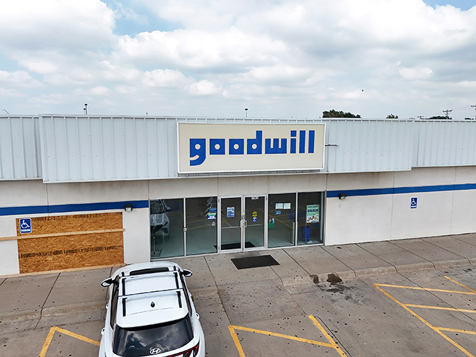 The blue Goodwill sign beckons like a lighthouse for bargain hunters navigating the sea of retail markup. Treasure awaits inside!