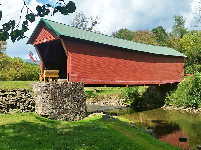 The Clover Hollow Covered Bridge stands like a crimson sentinel against Virginia's rolling hills, its reflection dancing in the stream below.