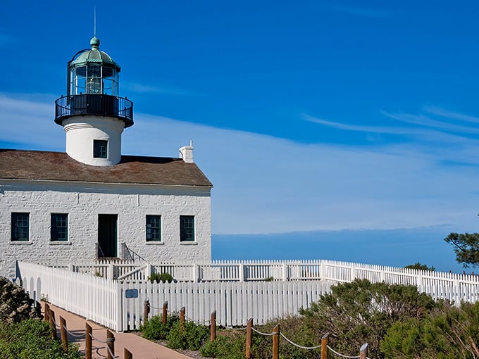 The Old Point Loma Lighthouse stands like a maritime sentinel, its pristine white walls and emerald dome gleaming against California's impossibly blue sky.