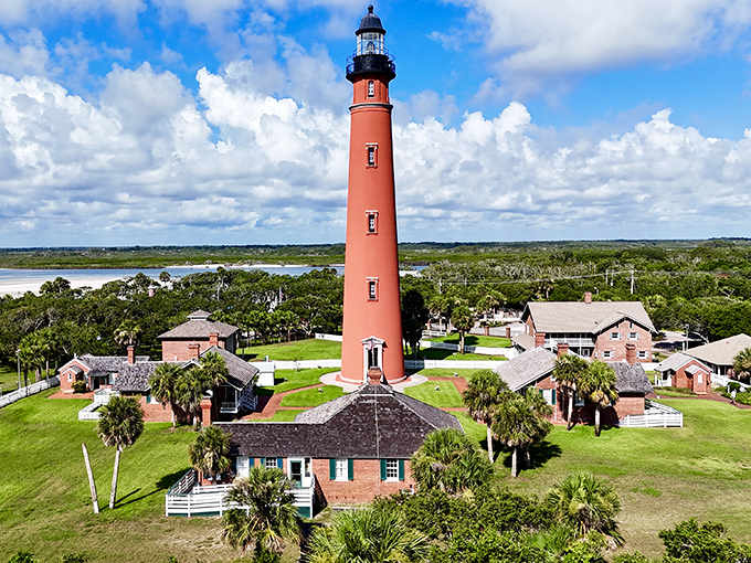 Florida's tallest lighthouse stands like a coral-colored exclamation point against the sky, surrounded by keeper's cottages and swaying palms.
