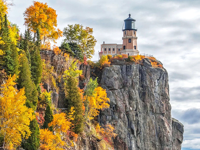 Nature's perfect frame: autumn's golden embrace cradles this iconic lighthouse perched dramatically on Minnesota's rocky North Shore. Mother Nature showing off her interior design skills.