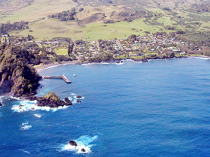 Aerial paradise: Hana's coastline unfolds like nature's perfect postcard, where the deep blue Pacific meets lush green hills in a dance as old as time itself.