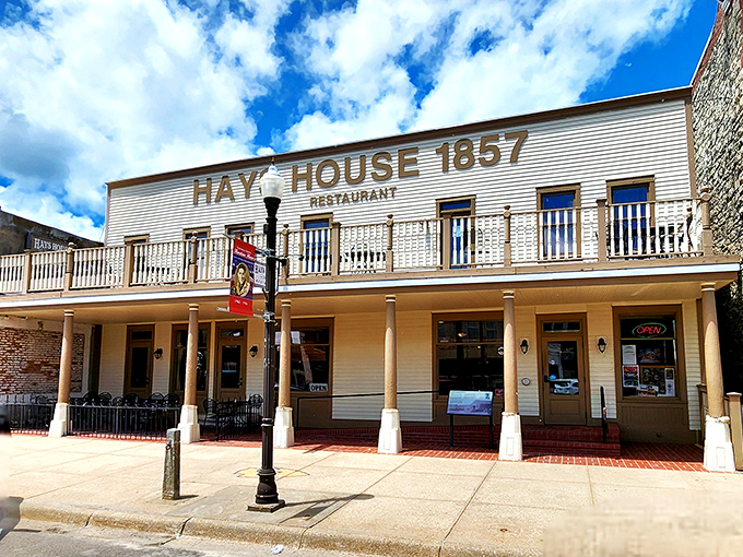 The historic facade of Hays House 1857 stands proudly against a Kansas sky, its balcony and columns whispering tales of Santa Fe Trail travelers who stopped here centuries ago.