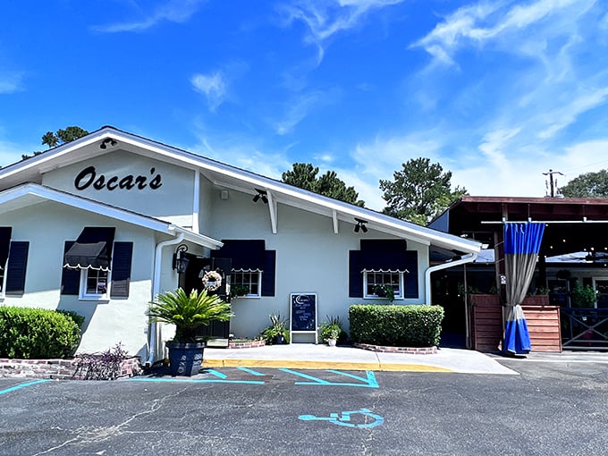 Oscar's welcomes you with Southern charm under brilliant blue skies, its classic white exterior and black awnings promising culinary delights within. The outdoor seating area beckons for those perfect Carolina evenings.