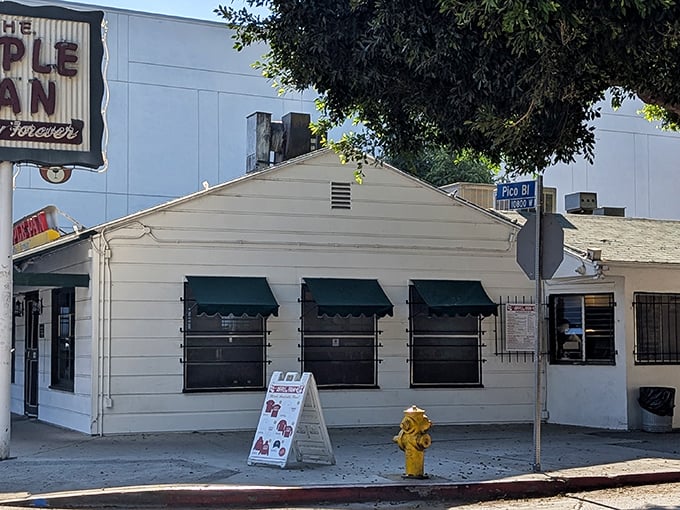 The unassuming white exterior of The Apple Pan stands like a time capsule on Pico Boulevard, its vintage sign promising "Quality Forever."