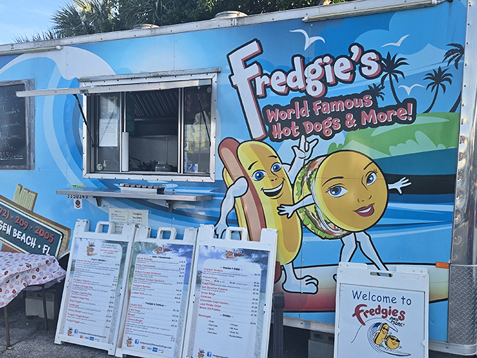The bright blue food trailer with cartoon hot dog mascots promises a flavor adventure that belies its humble size. Florida sunshine included at no extra charge!
