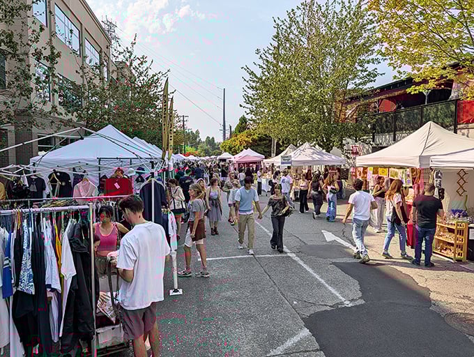 Sun breaks through Seattle clouds, illuminating a bustling marketplace where vintage fashion meets artisanal crafts under a canopy of white tents.