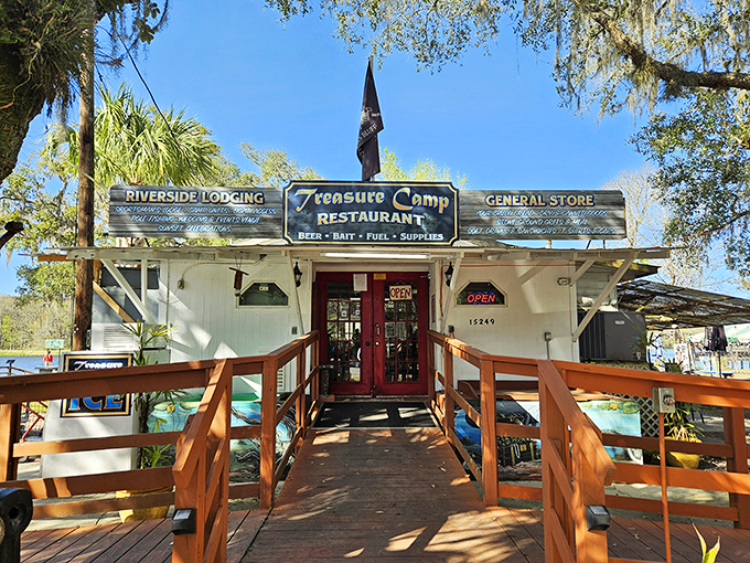 The wooden walkway to Treasure Camp feels like crossing into a Florida time capsule – rustic charm with a side of adventure awaits beyond those red doors.