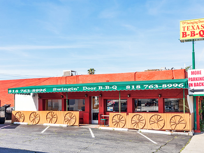 The bright orange-red exterior of Swinging Door BBQ stands out like a beacon for meat lovers in North Hollywood. Those wagon wheels aren't just for show!