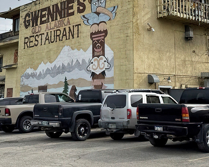 The unmistakable yellow exterior of Gwennie's, with its hand-painted totem pole and mountain scene, promises authentic Alaskan comfort within.