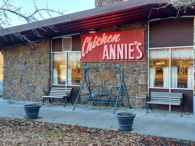 The iconic red sign against weathered stone promises a fried chicken pilgrimage worth every mile of Kansas backroad.