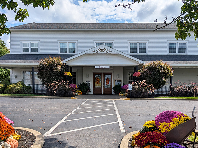 The welcoming facade of Amish Door Restaurant, where seasonal blooms and harvest decorations greet hungry travelers like old friends waiting to share a feast.