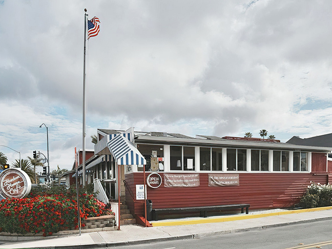 The iconic red exterior of Harbor House Cafe stands like a beacon of comfort food along PCH, complete with blue-and-white striped awnings that scream "classic Americana."