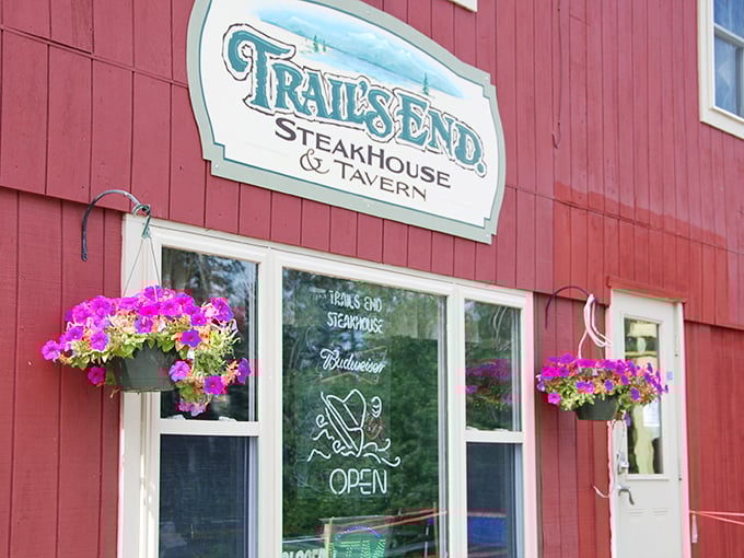 The classic red exterior of Trail's End beckons like a culinary lighthouse in Maine's wilderness, complete with cheerful hanging flower baskets.