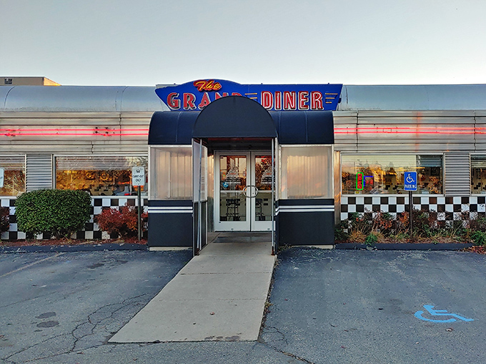 Neon dreams come true at The Grand Diner's entrance, where that classic checkerboard pattern promises authentic American comfort.