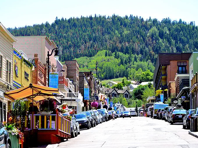 Historic buildings line Park City's bustling Main Street, where Victorian architecture meets modern mountain culture against a backdrop of evergreen hills.