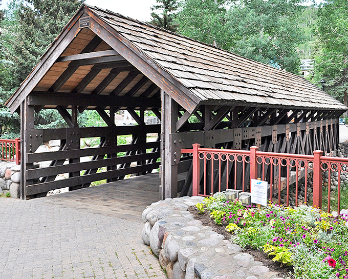 The classic wooden lattice design of Vail's covered bridge offers a perfect frame for your Colorado mountain memories, complete with charming red railings and stone foundations.