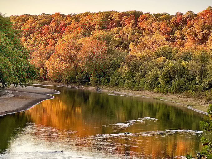 Fall's fiery palette reflects perfectly in the calm waters, creating a double feature of autumn splendor that no Instagram filter could improve upon.