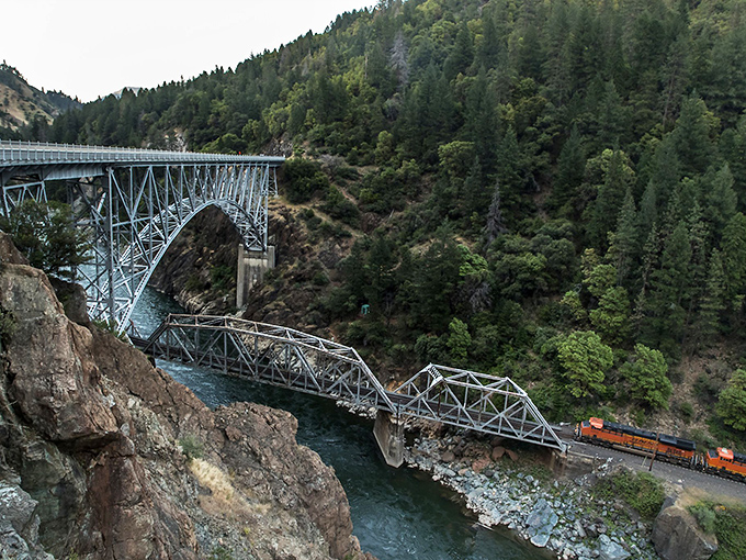The railroad bridge and highway create a mesmerizing triple-decker effect. Like a layer cake of transportation where trains get the best view.