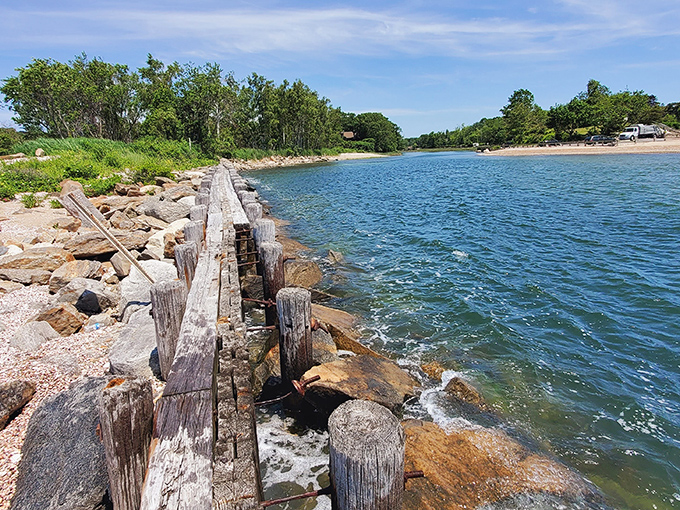 Weathered wooden jetties stand like sentinels against the tide, creating that perfect blend of rustic charm and coastal engineering that defines New England shores.