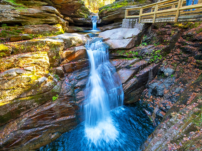 Nature's perfect choreography in action. Sabbaday Falls cascades over ancient rock formations, creating a mesmerizing dance of water and light that hypnotizes visitors.