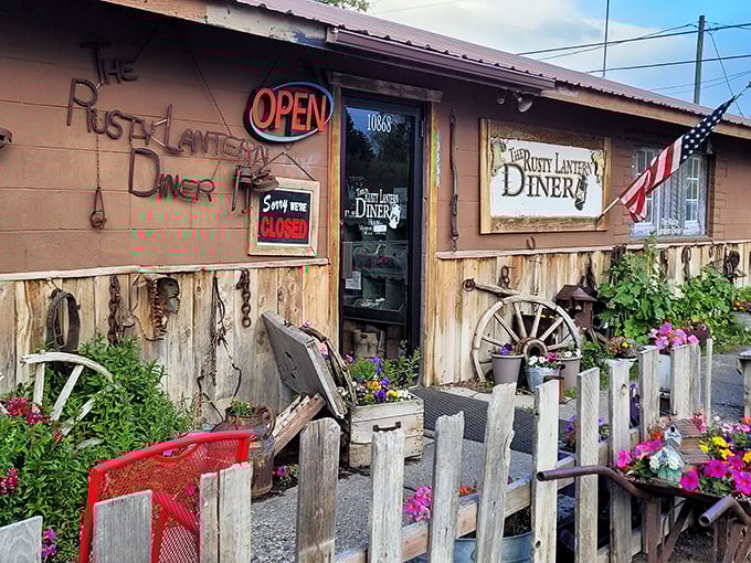 The rustic charm of Rusty Lantern's exterior feels like stepping into a Western movie set, complete with weathered wood, wagon wheels, and flowers that soften the frontier vibe.