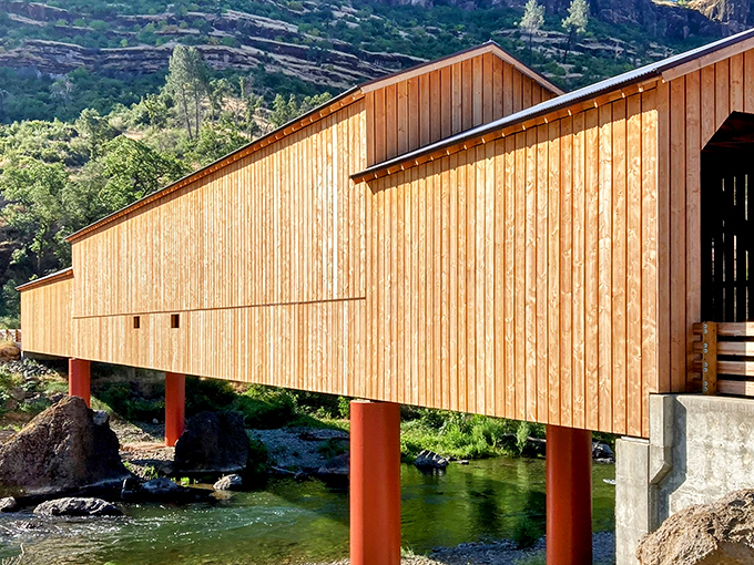 The honey-colored wooden exterior gleams in the California sunshine, spanning Butte Creek like a postcard from a simpler time.