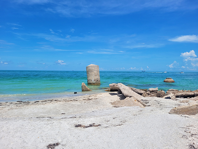 Mother Nature's own infinity pool where turquoise waters meet pristine white sand. Those concrete remnants? Just ancient history casually sunbathing alongside you.