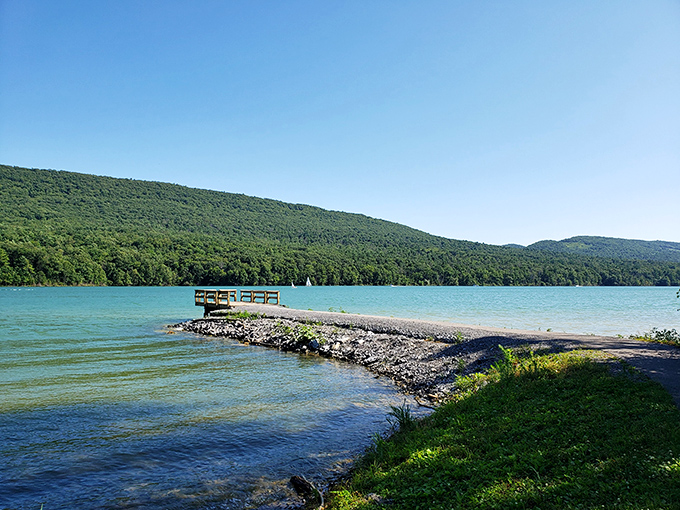 A stone jetty stretches into crystal-clear waters, inviting adventurers to venture closer to those emerald mountains. Nature's version of the red carpet.