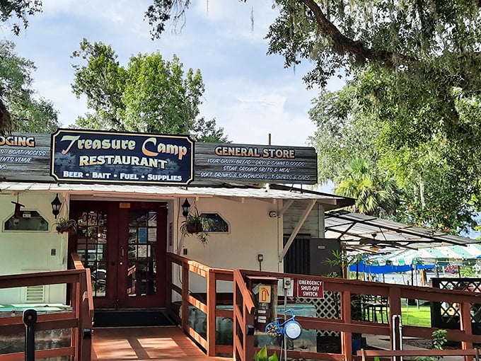 Framed by lush Florida greenery, Treasure Camp's weathered sign promises three essentials for river life: food, supplies, and stories you'll retell for years.