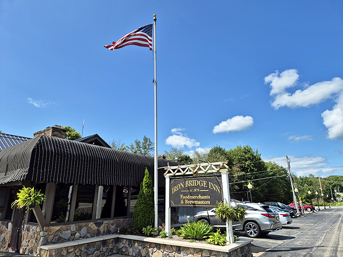 The Iron Bridge Inn stands proudly under Pennsylvania's blue skies, its distinctive black awnings and stone foundation promising culinary adventures within.
