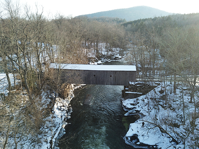 Winter drapes Bulls Bridge in a quiet blanket of snow, transforming the wooden passage into a monochromatic masterpiece against the frozen landscape.