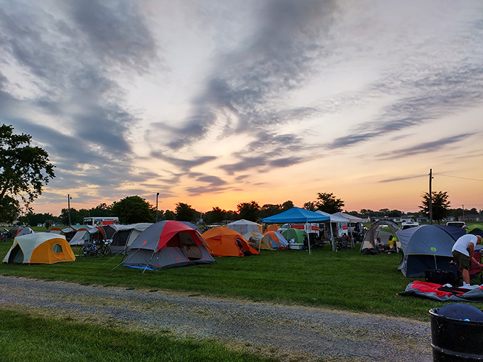 Sunset paints the sky above a field of colorful tents, where community camping creates memories brighter than any campfire.