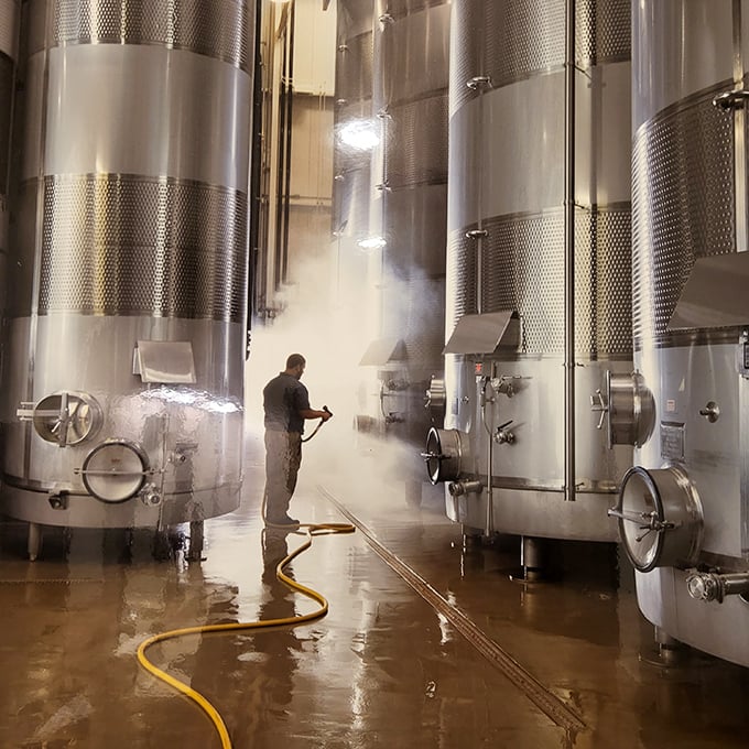 Steam rises dramatically as a worker sanitizes massive tanks&mdash;winemaking's less glamorous side still makes for compelling theater.