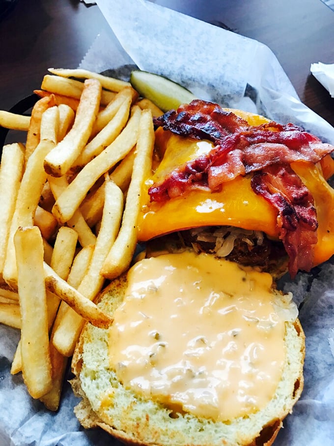 This burger isn't just food&mdash;it's architecture. Melty cheese cascading over bacon and beef with fries standing guard nearby. Napkins required.