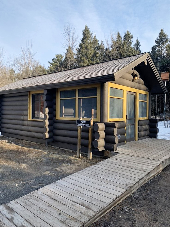The camper's cabin stands ready for adventure in any season, its log walls promising cozy shelter after a day of exploration.