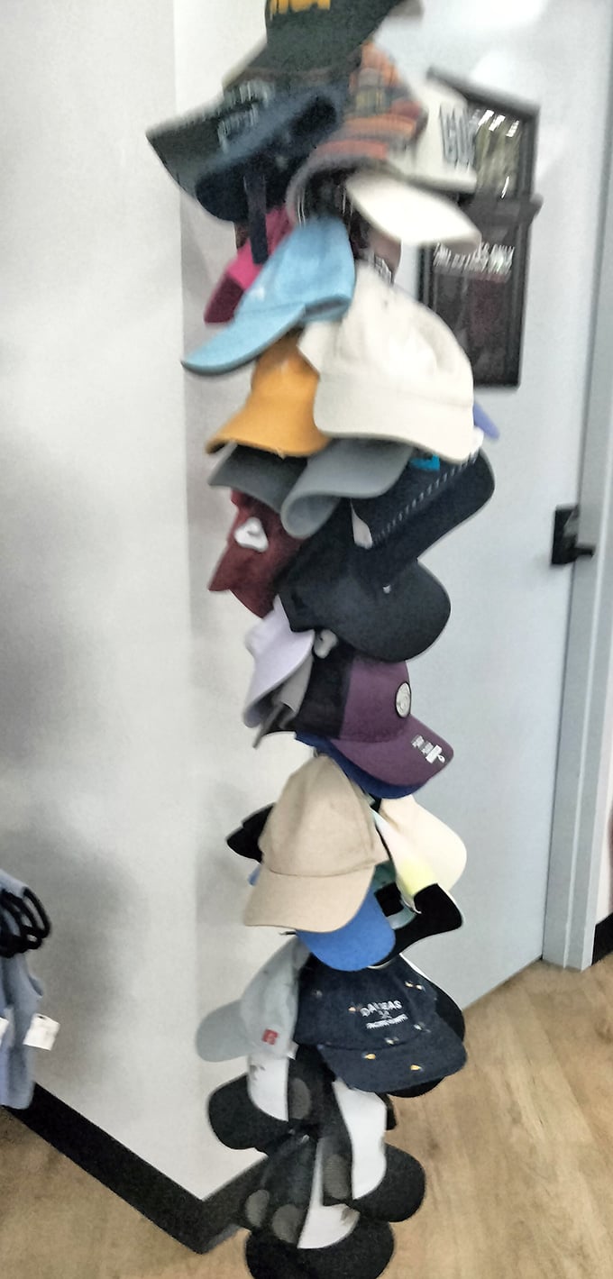 Baseball caps stacked on a tower like a wobbly monument to casual headwear&mdash;practical storage meets quirky store personality.