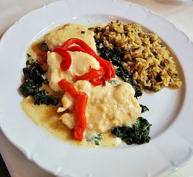 Chicken nestled in creamy sauce with vibrant red peppers. The wild rice alongside isn't just playing defense&mdash;it's soaking up sauce like it's getting paid overtime.