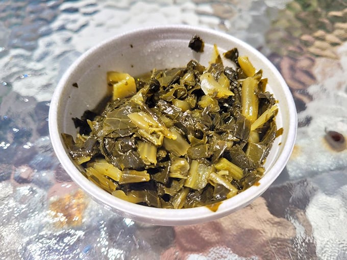 Collard greens that have been cooking longer than most pop stars' careers. The vinegary tang cuts through rich barbecue like a dream.