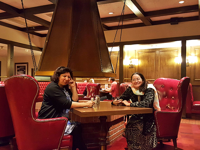 Two diners enjoying the timeless comfort of red leather booths&mdash;where conversations flow as freely as the coffee refills.