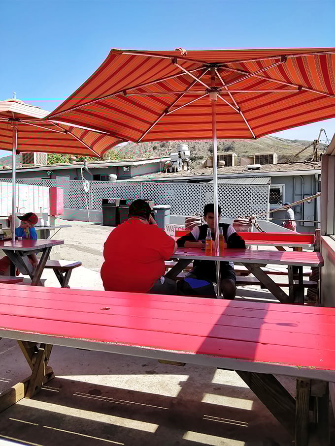 Striped umbrellas provide shade for seafood enthusiasts. At these picnic tables, strangers become friends united by the universal language of "mmm."